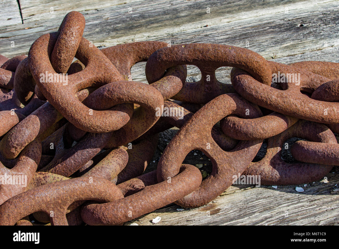 Rusty anchor chain on a wooden dock Stock Photo - Alamy