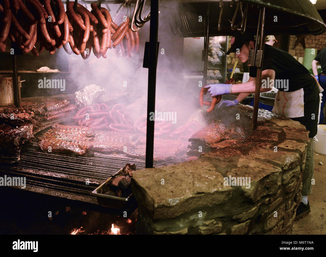 Meat smoking in open pit for bar-b-que Stock Photo - Alamy