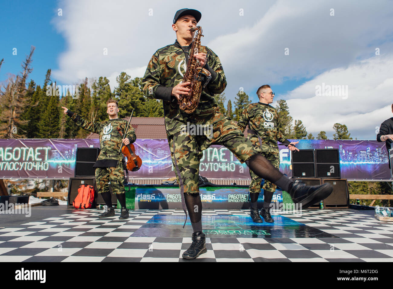 Three musicians dancing and playing violin and saxophone on the stage ...