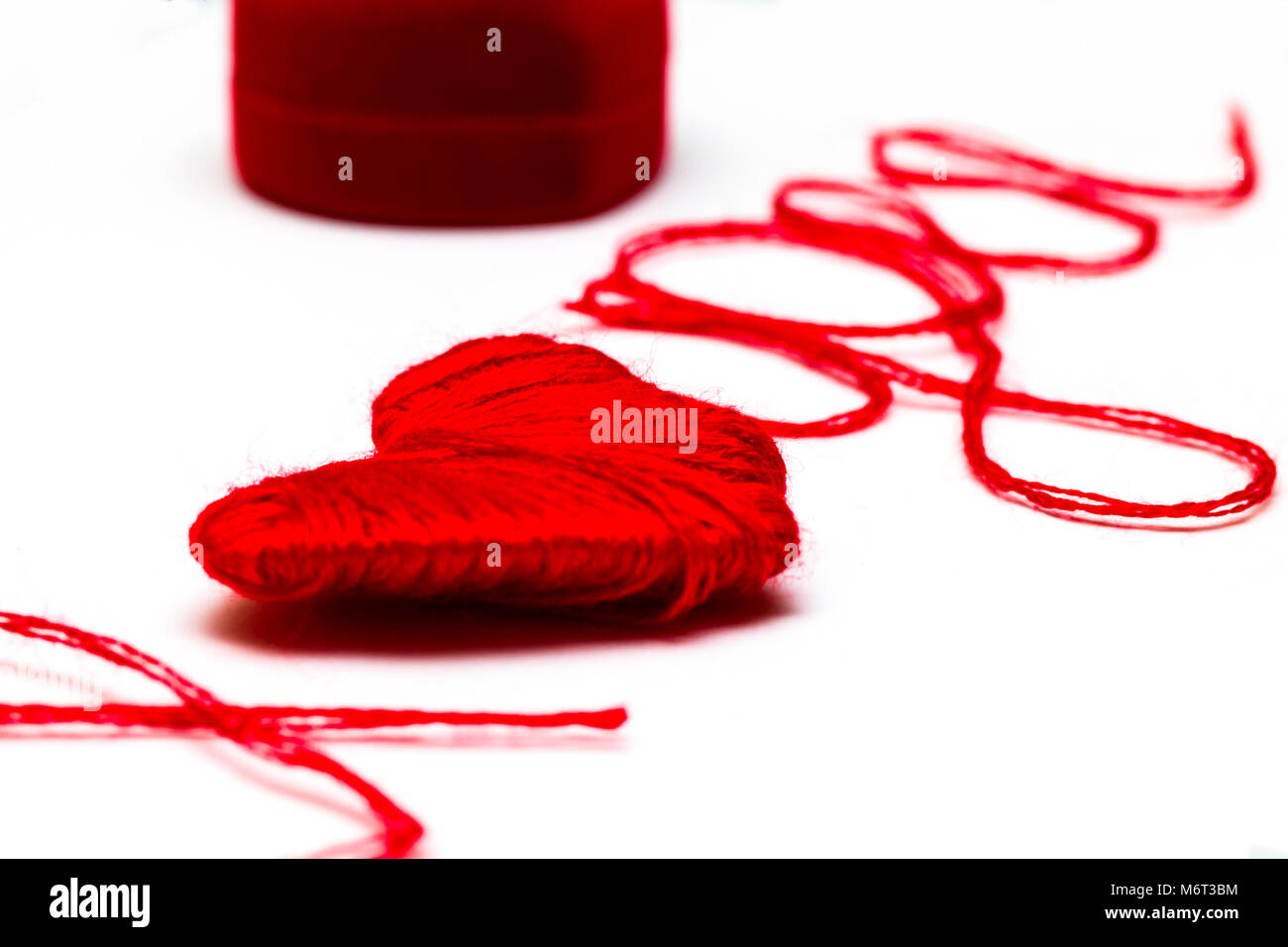 Love you words and heart symbol made of red thread on a white ...