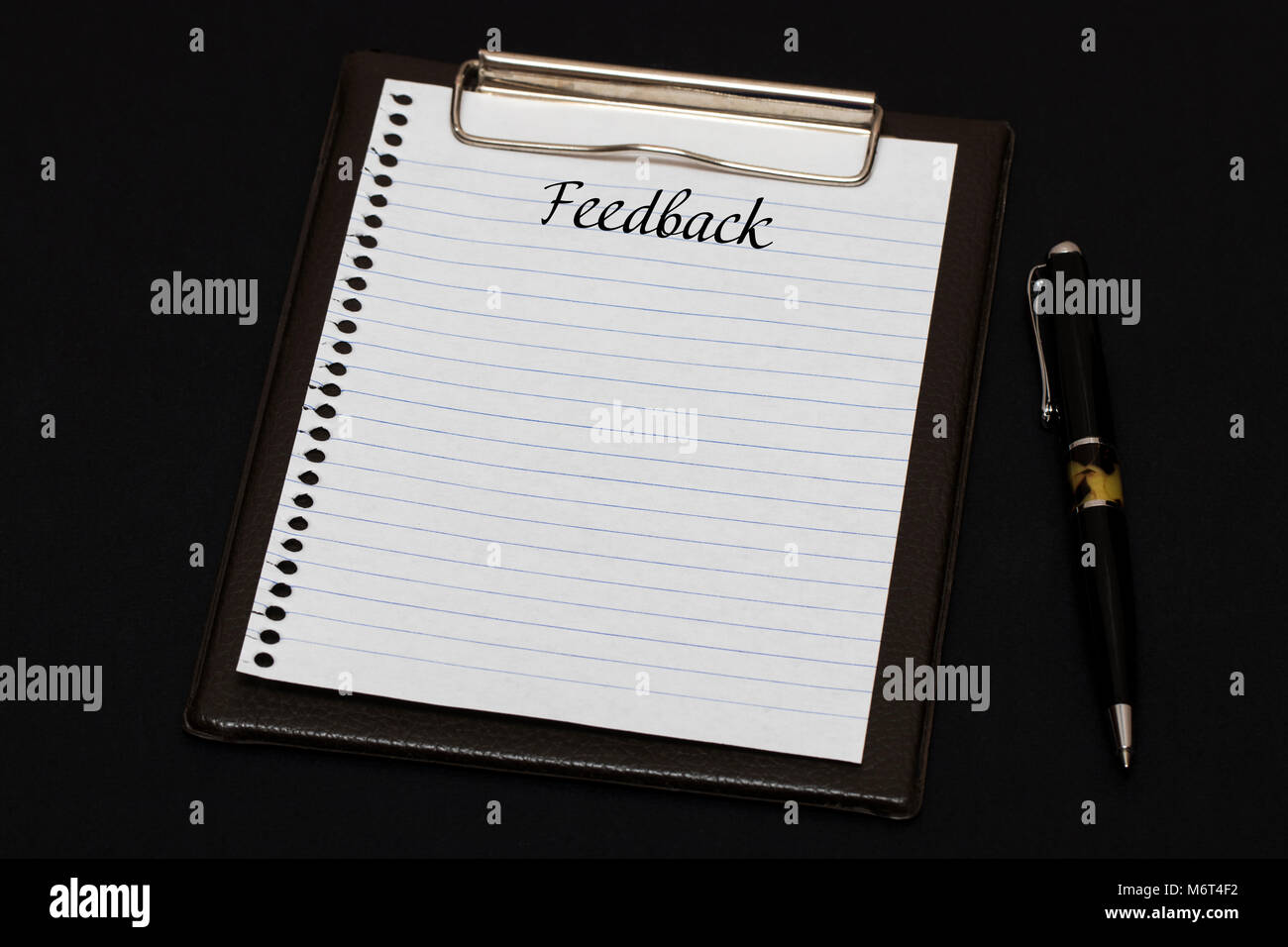 Top view of clipboard and white sheet written with Feedback on black ...