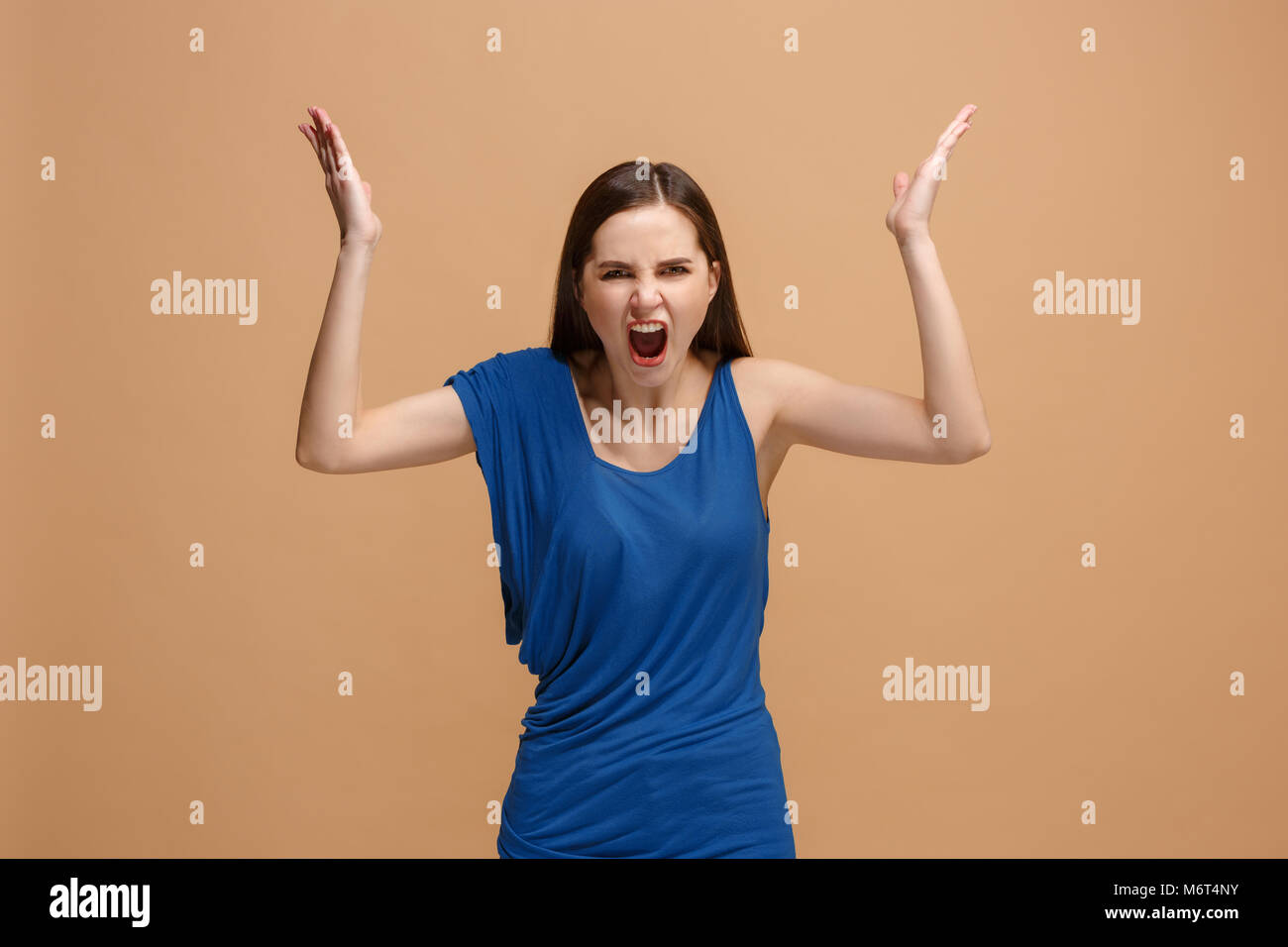 The young emotional angry woman screaming on pastel studio background ...