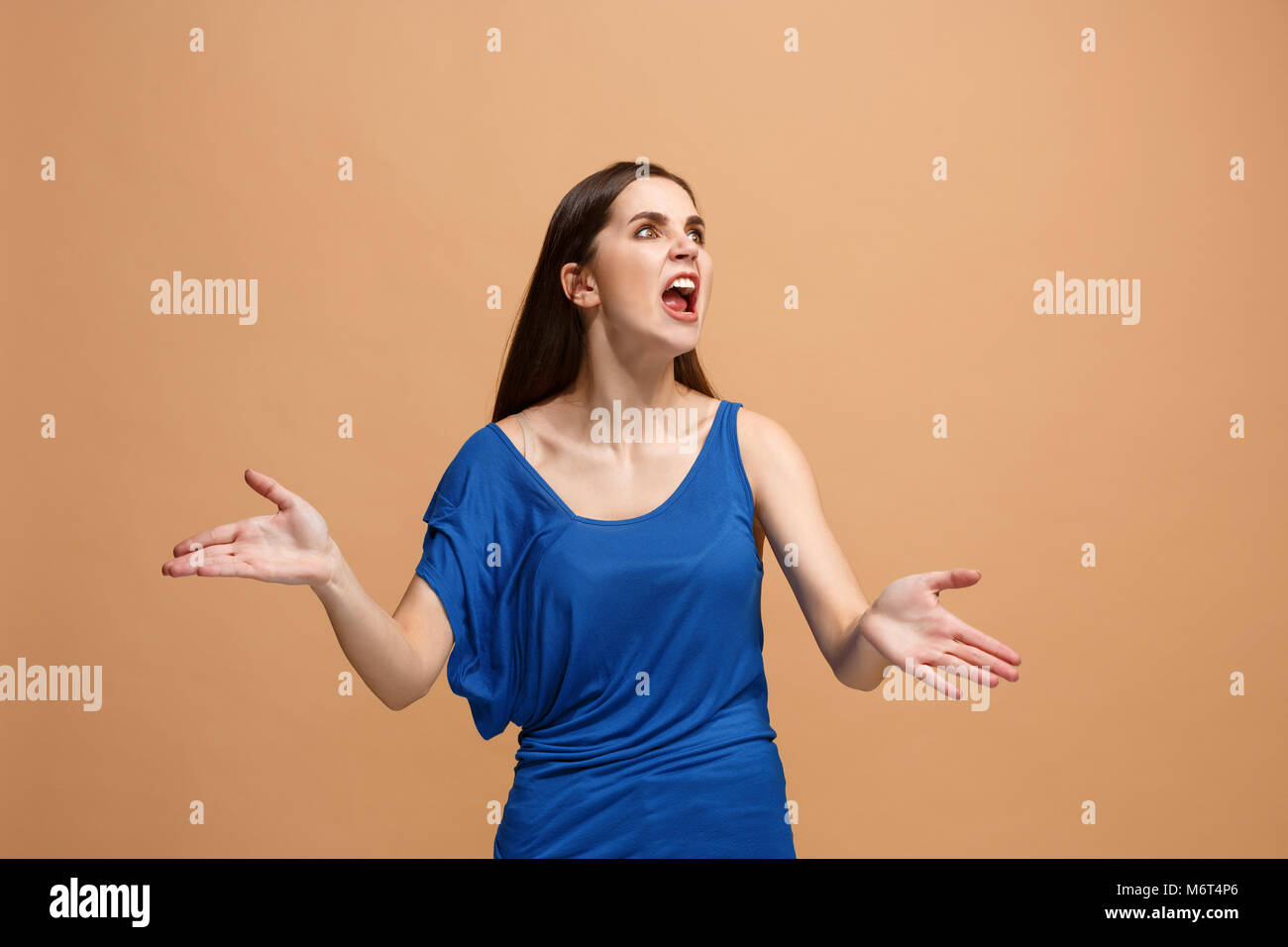 The young emotional angry woman screaming on pastel studio background ...