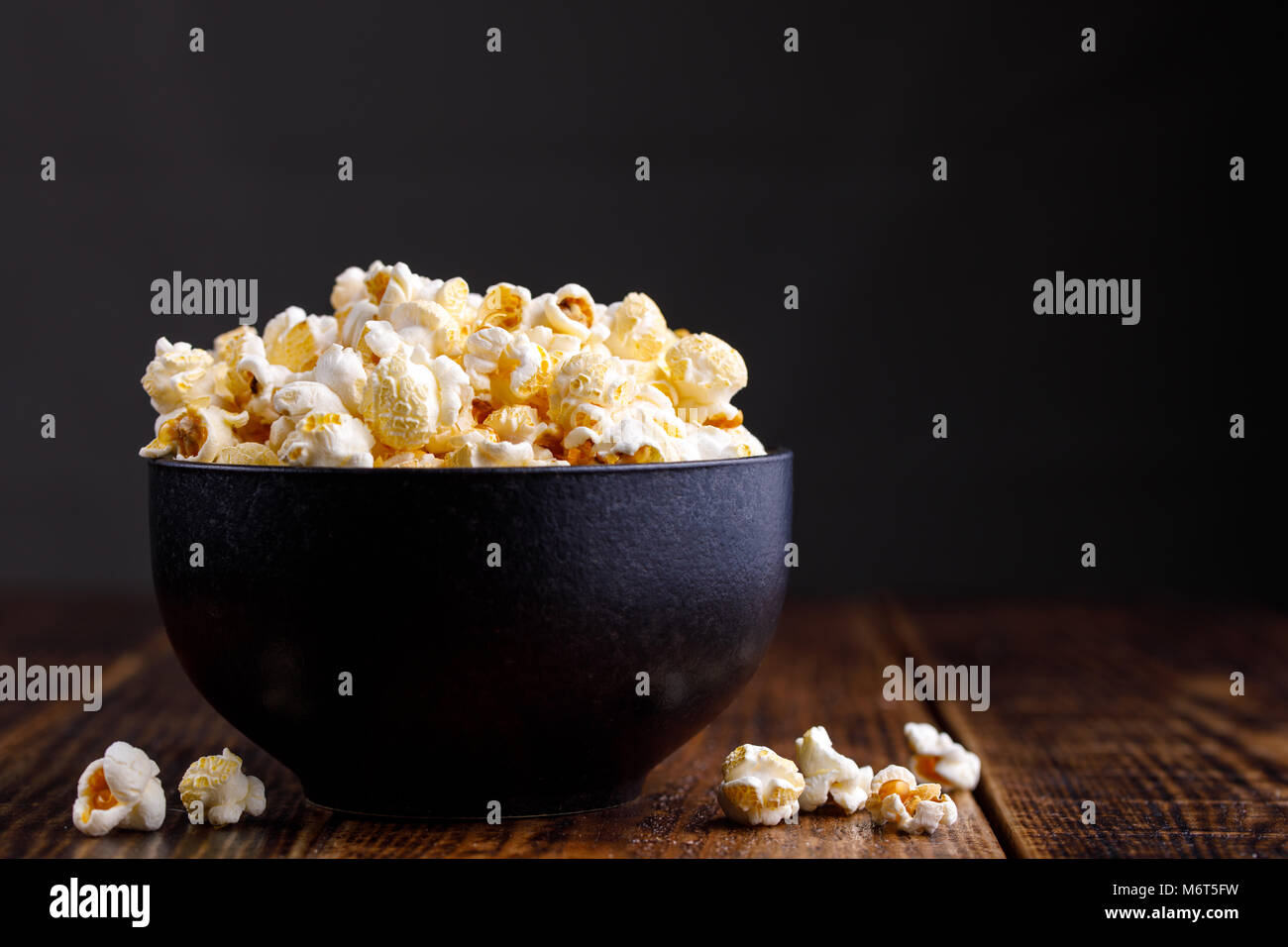 Popcorn in a ceramic bowl and scattered on a wooden background Stock ...