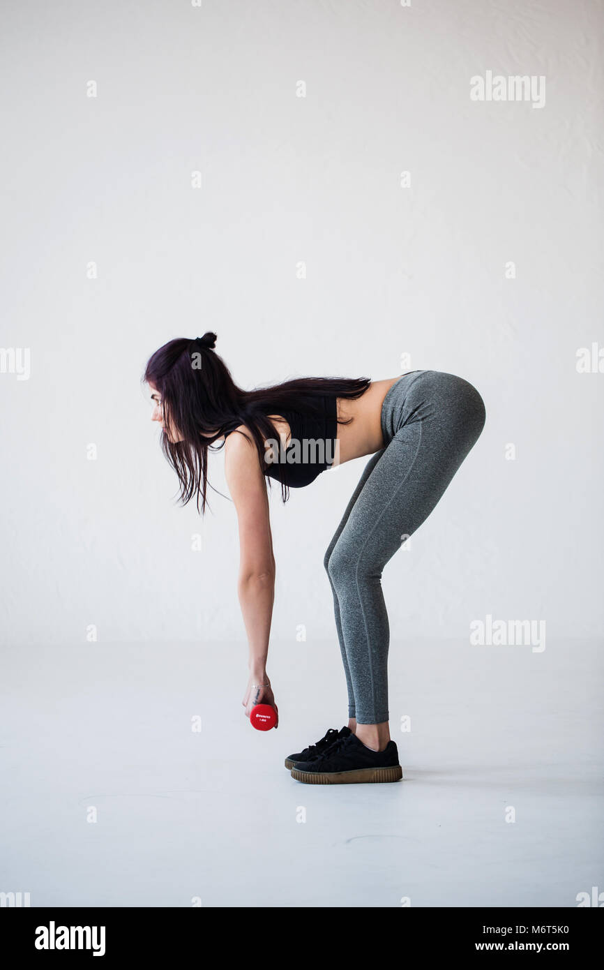 Full-length side photo of the sportwoman bending with red dumbbells in ...