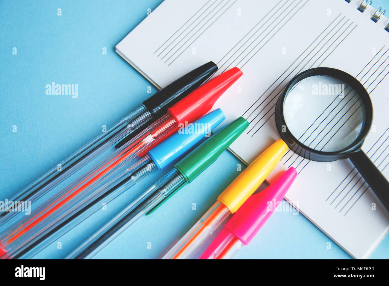 colored pens and magnifier on a white sheet of Notepad for text Stock ...