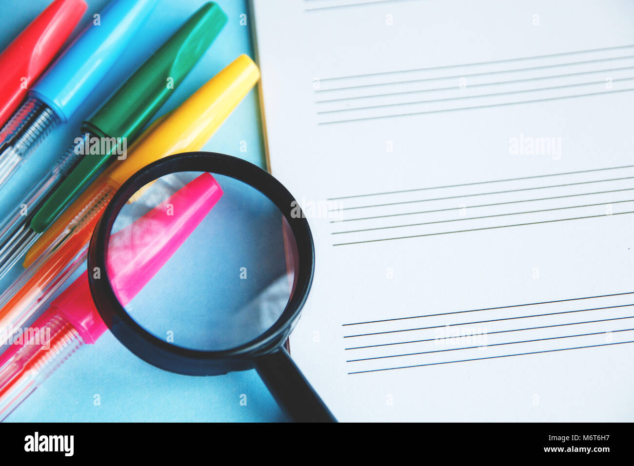 colored pens and magnifier on a white sheet of notepad for text Stock ...
