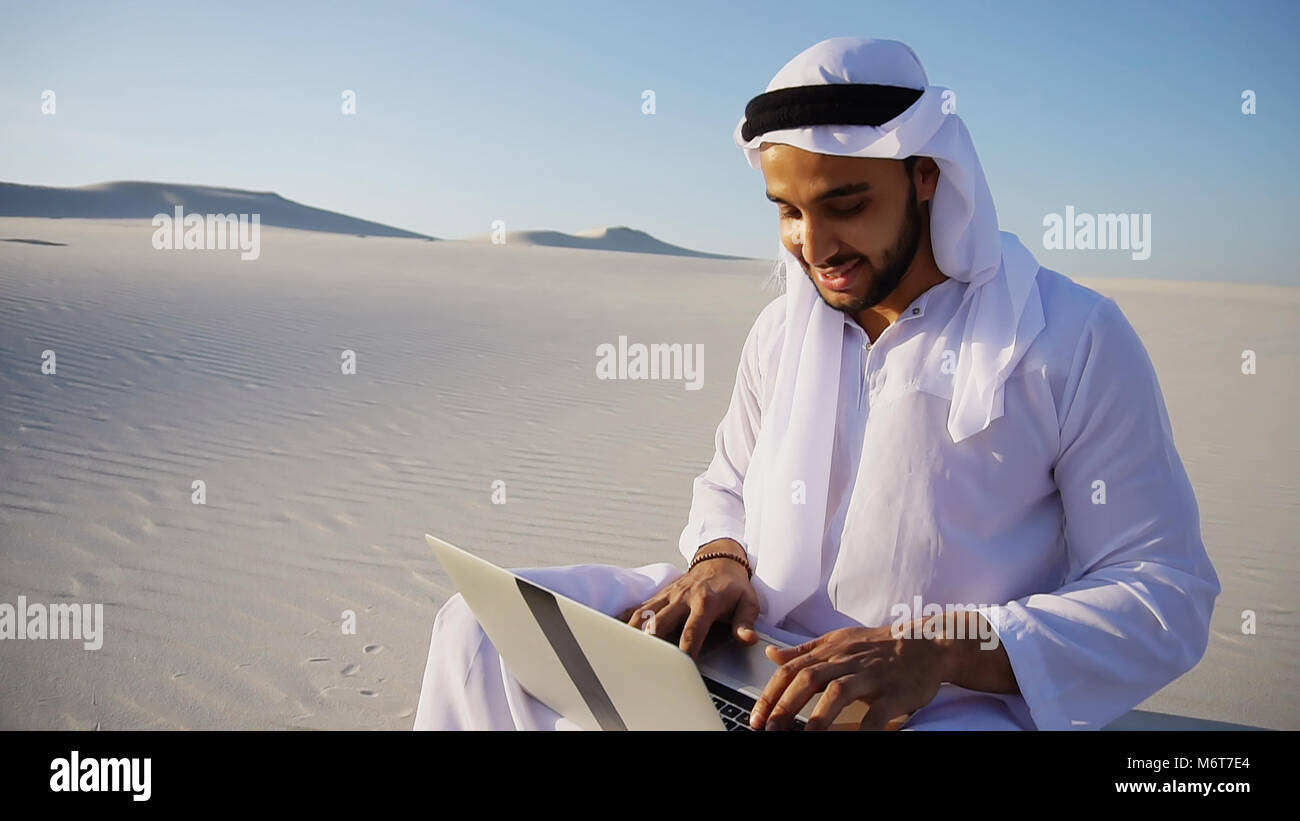 Educated male Muslim Arabian UAE Sheikh architect sits with gadg Stock ...