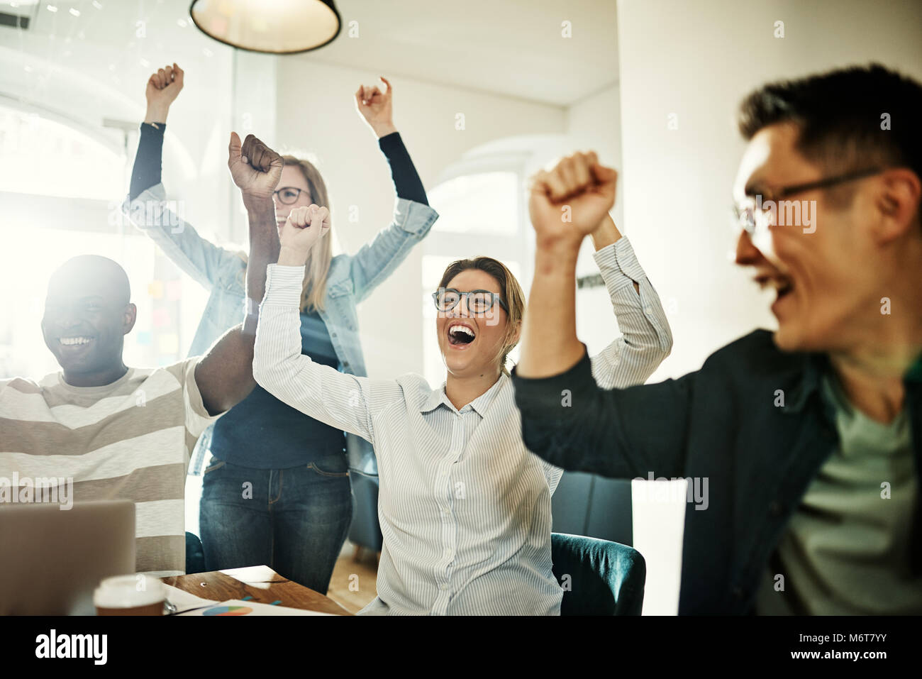 Diverse group of businesspeople cheering excitedly together during a ...