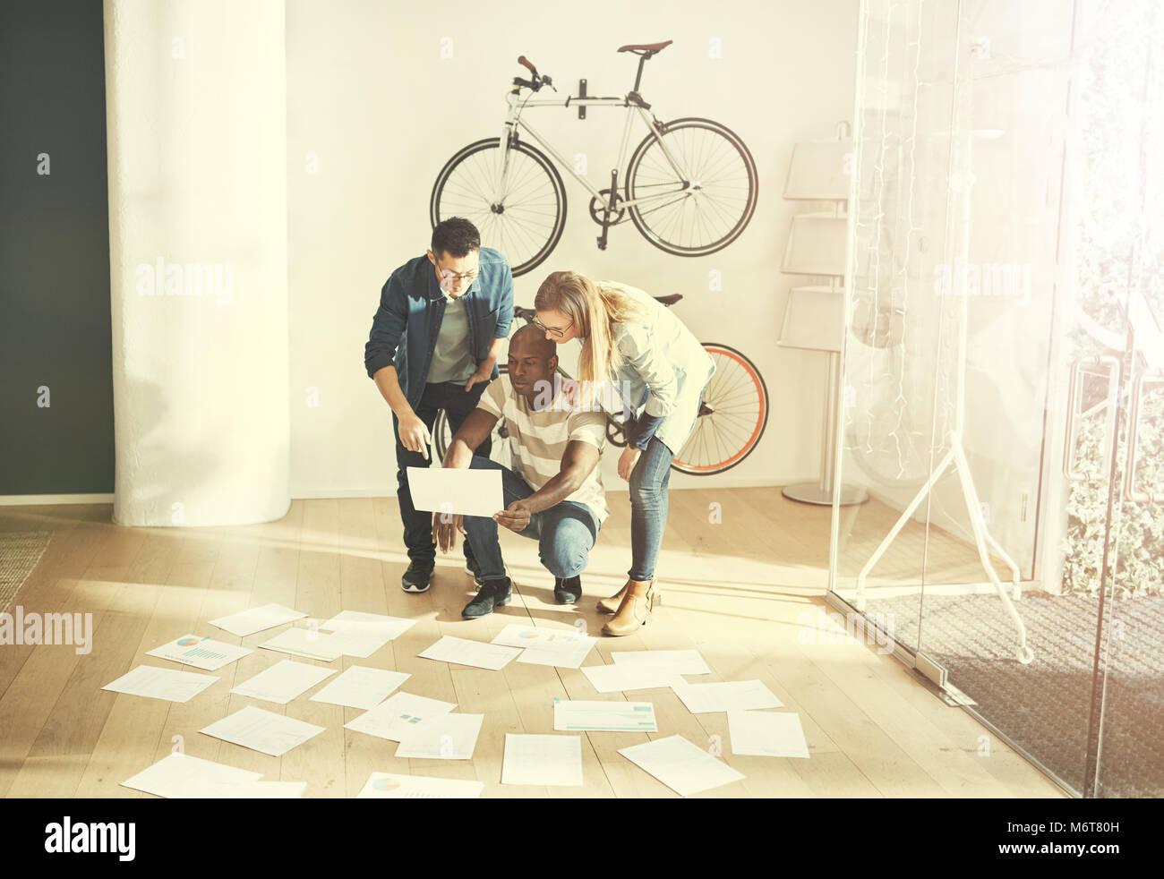 Three diverse colleagues standing in cool modern office reading ...