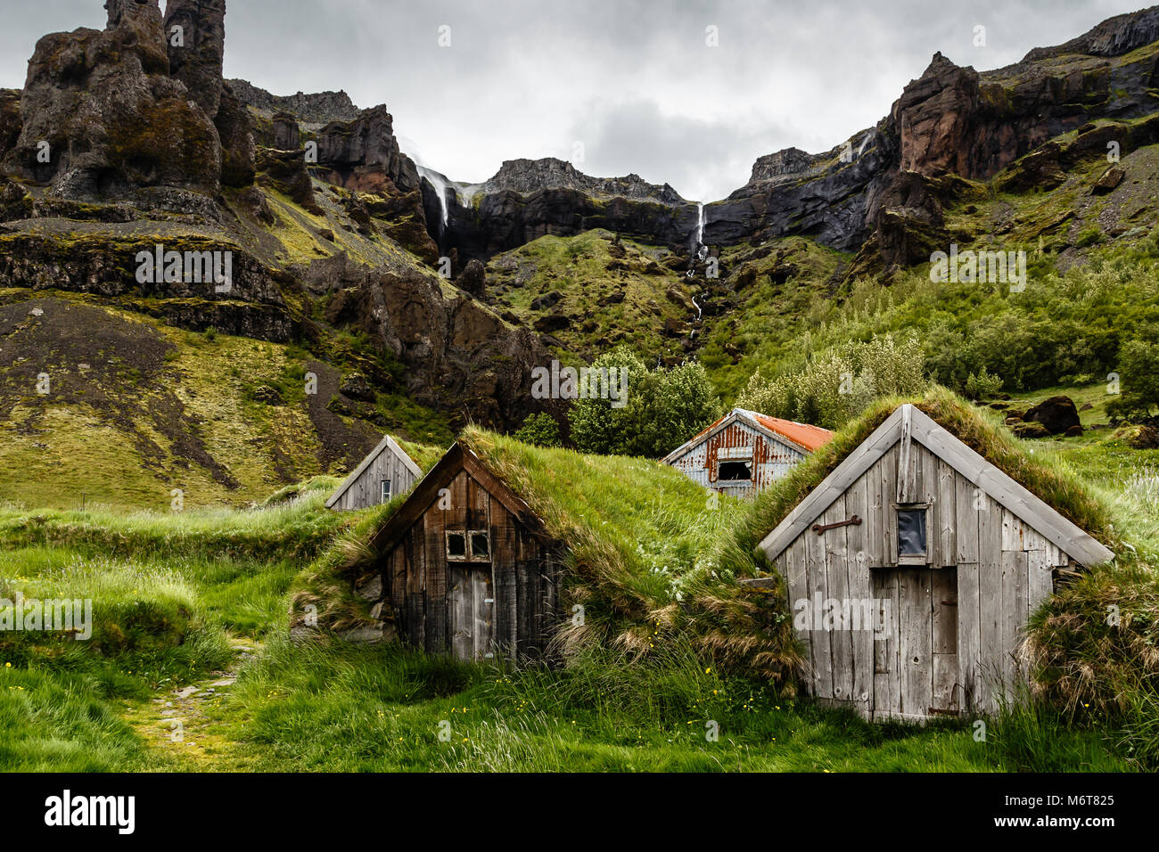 Icelandic turf houses and rocks with waterfall in the background near ...