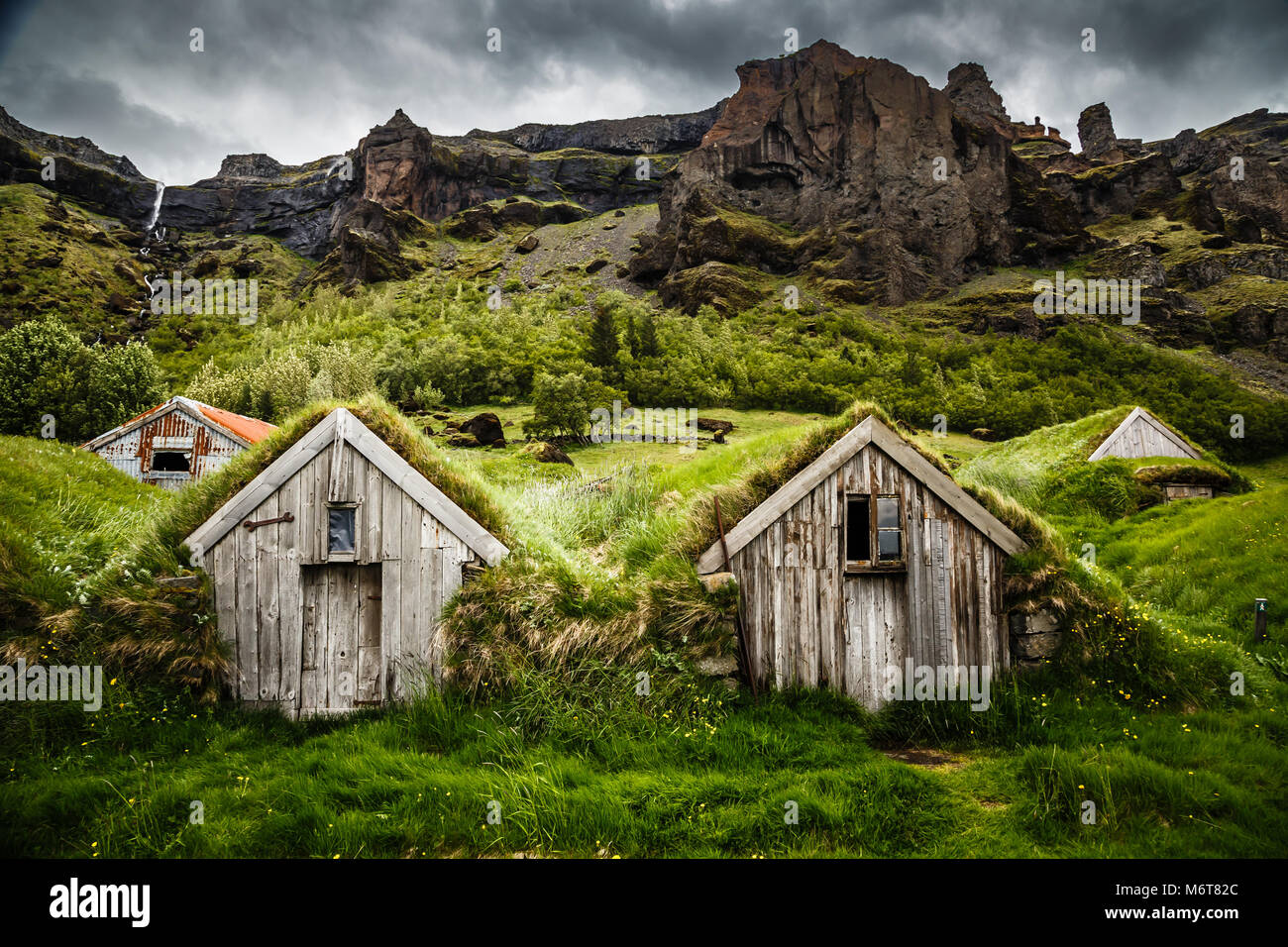 Icelandic turf houses and rocky canyon with waterfall in the background ...