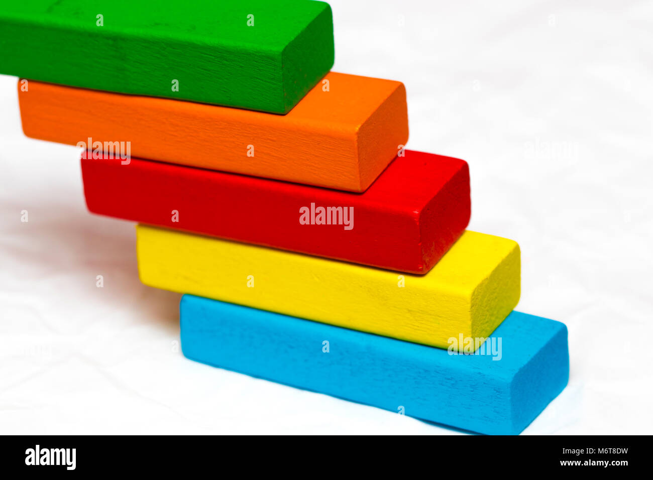 ladder made from colorful wooden blocks on a white background. The ...