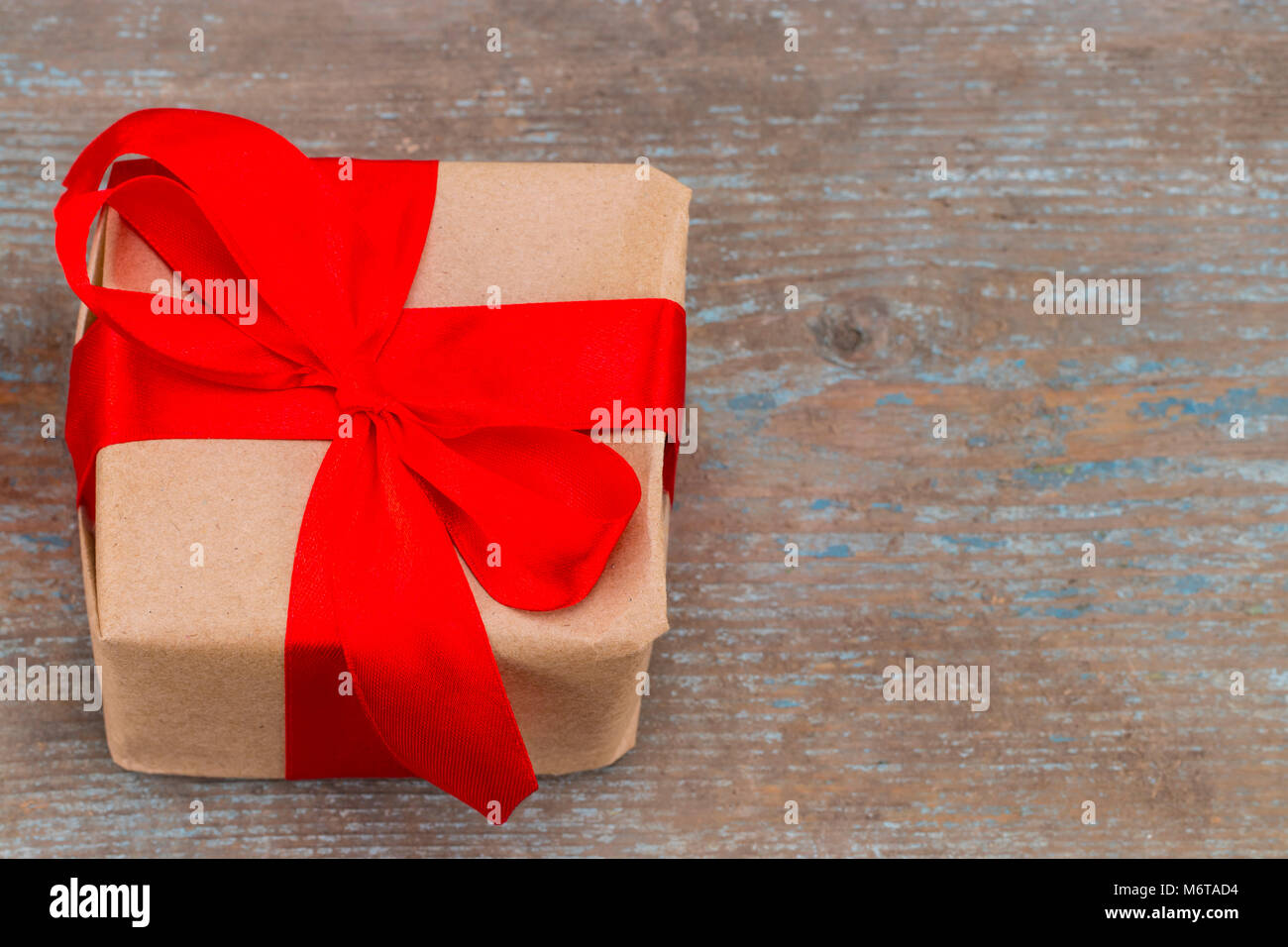 Gift box present with red bow ribbon and brown krafts wrapping paper on ...