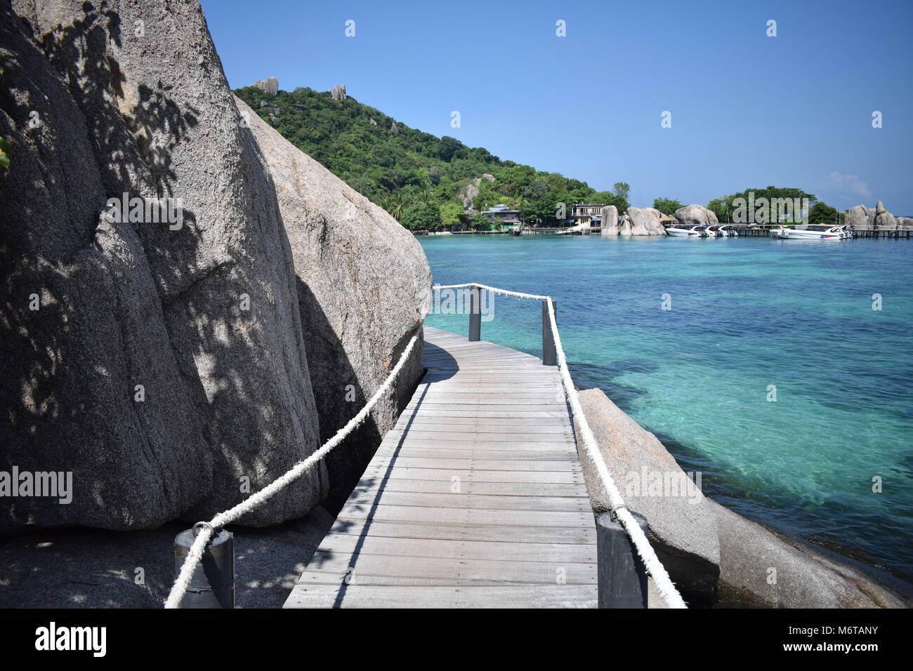 Wooden pier around between rocks and a cristal clear water with an ...