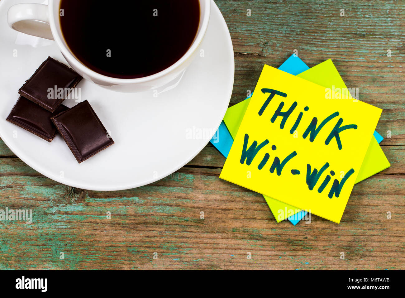 Think win-win concept - handwriting on a sticky note with a cup of ...