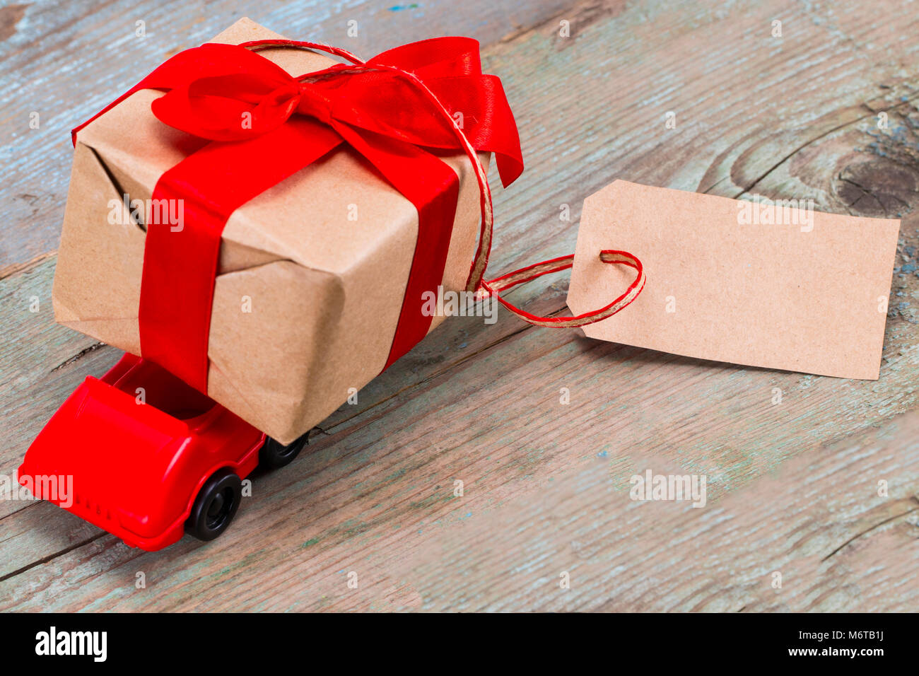 Red toy car delivering gifts box with tag with empty space for a text ...
