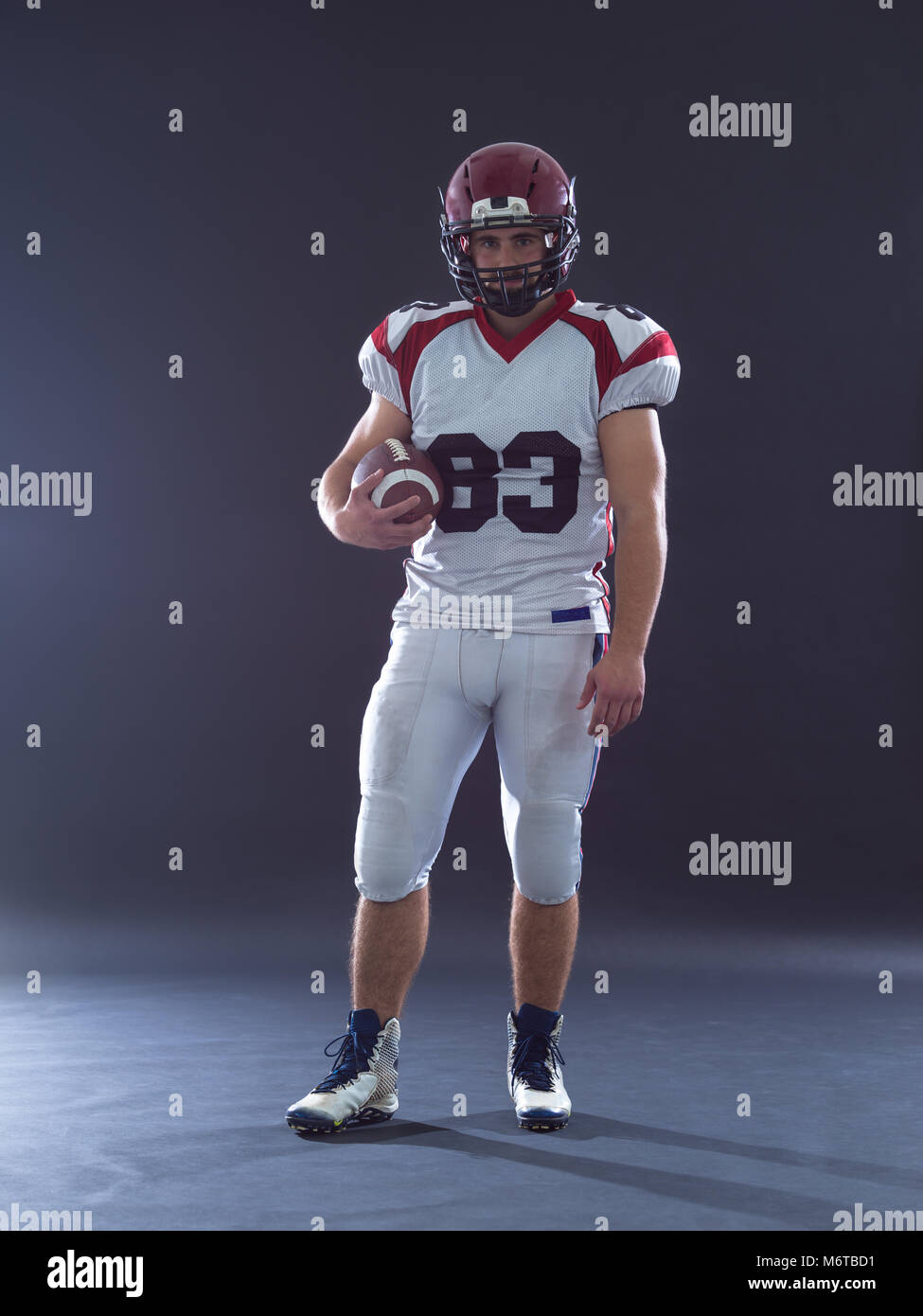 Portrait of a strong muscular American Football Player isolated on gray ...