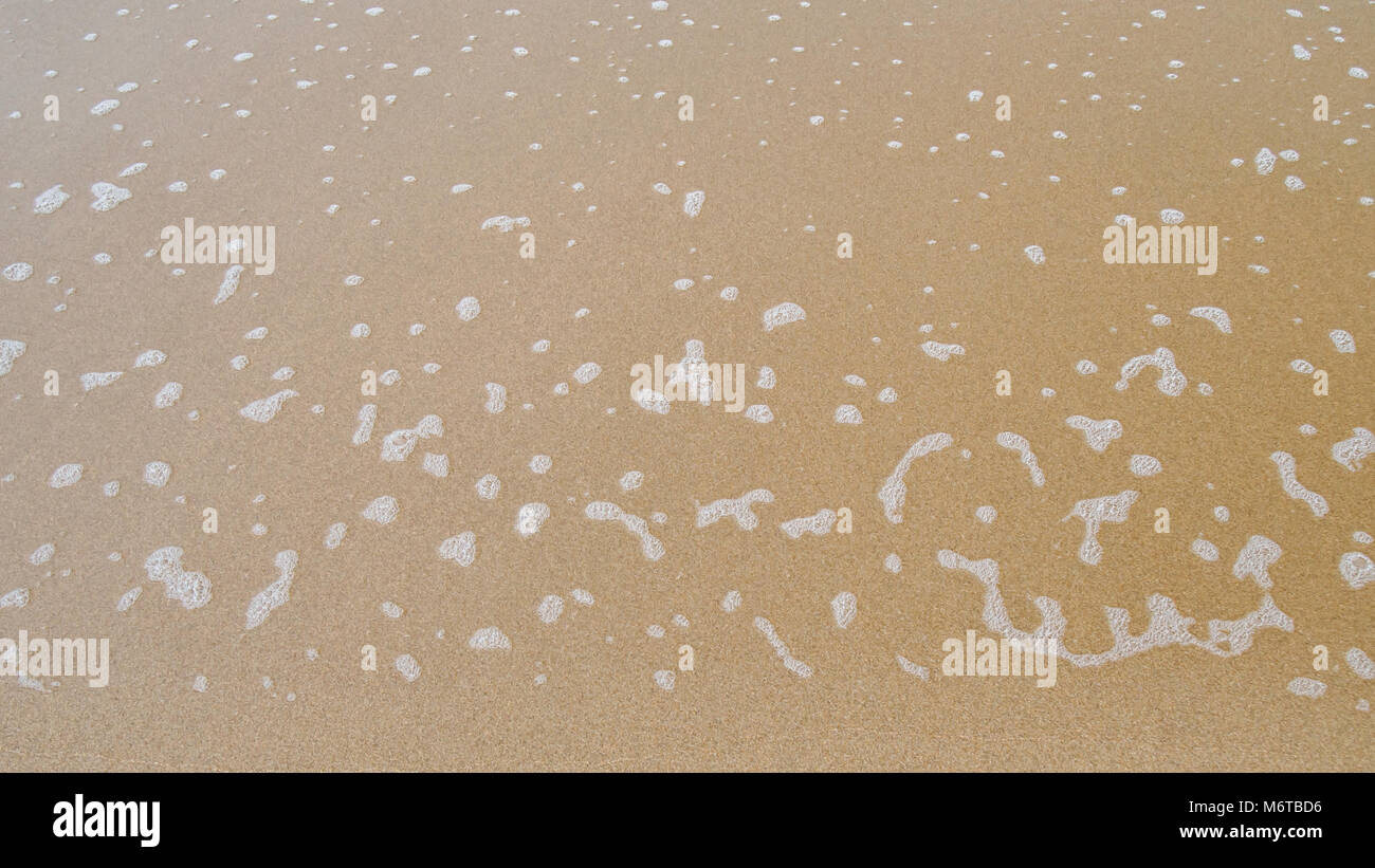 Sea foam on sand background Stock Photo - Alamy