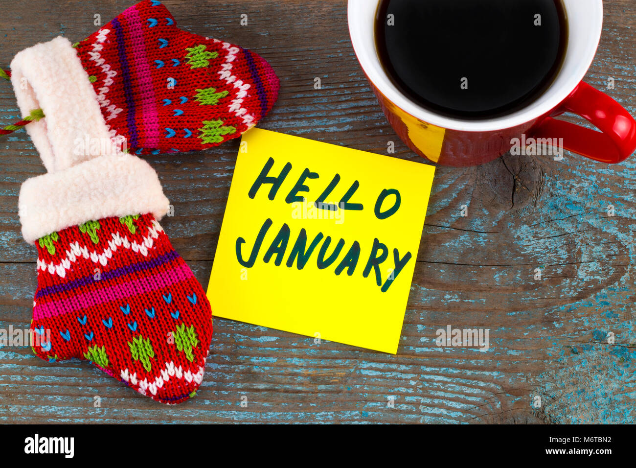 Hello January - handwriting in black ink on a sticky note with a cup of ...