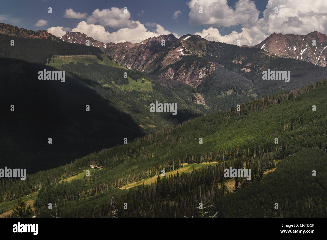Tree-covered Vail Mountain with blue skies and shadows cast from the ...