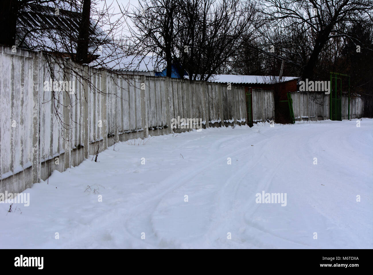 An old rickety concrete fence in winter in an abandoned and destroyed ...