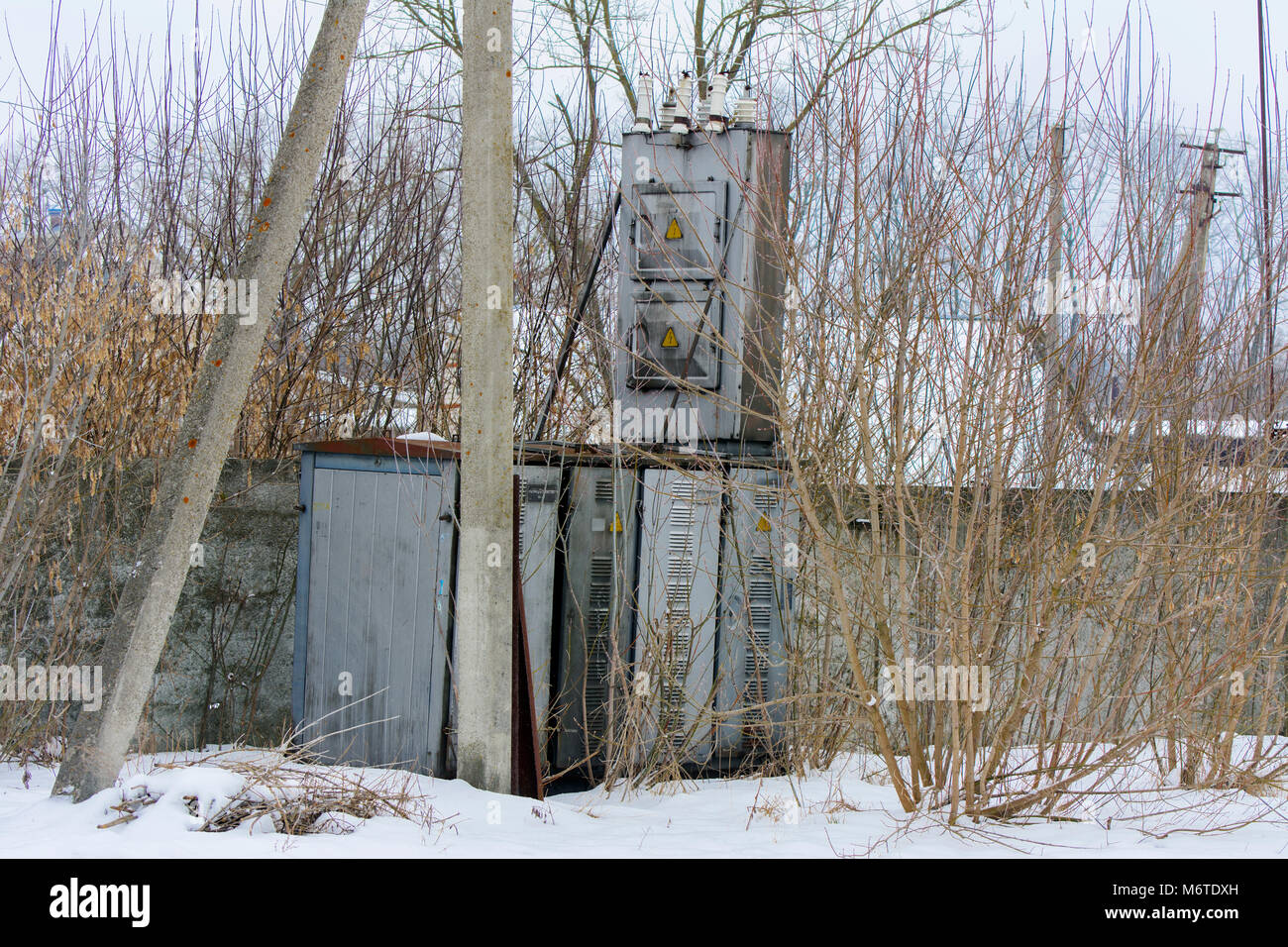 An old rusty transformer station in winter in an abandoned and ...