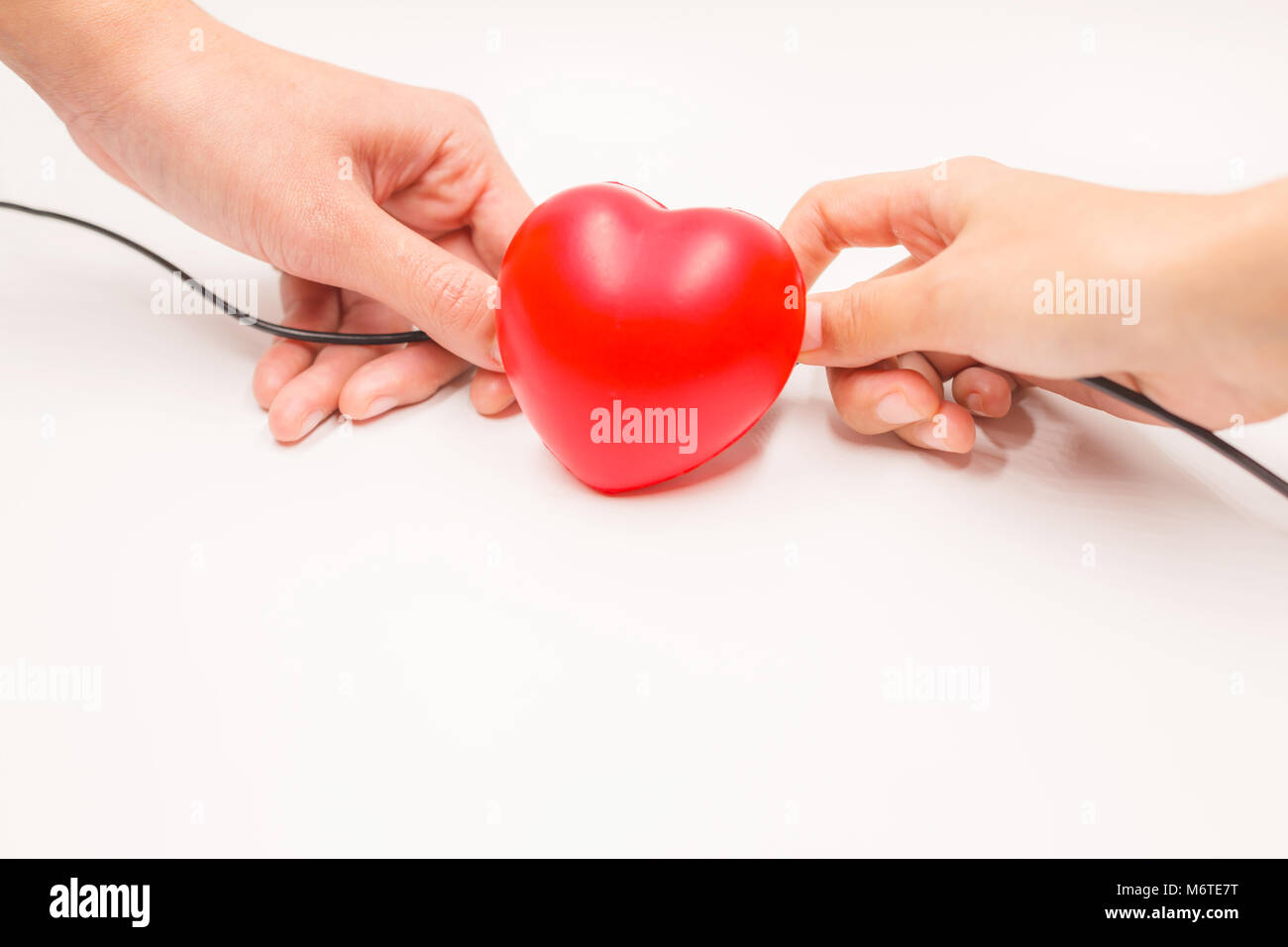 Hands with charging cables to help recovering heart on white background ...
