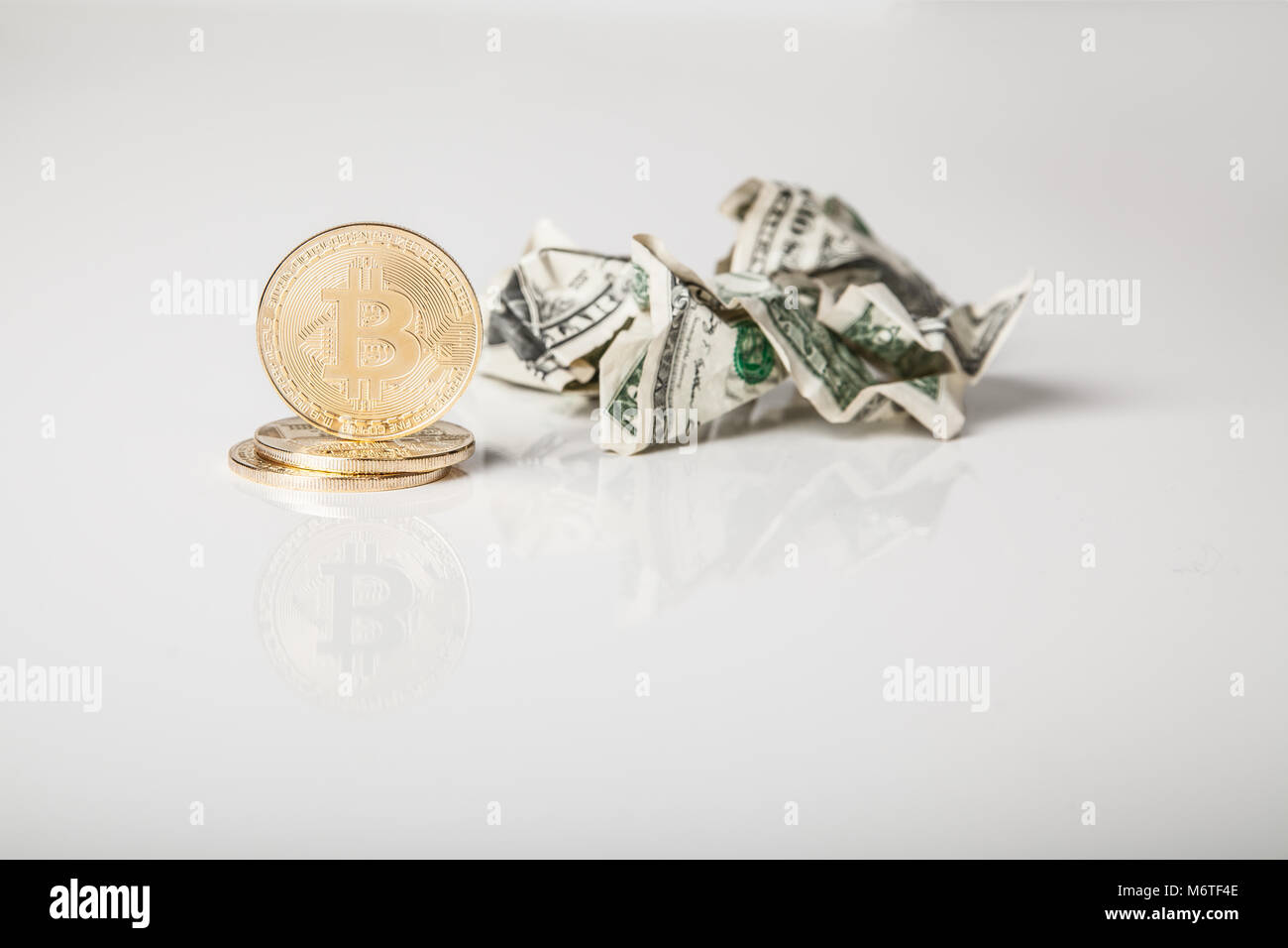 Crypto currency. Gold bitcoin coins and crumpled dollars on white ...
