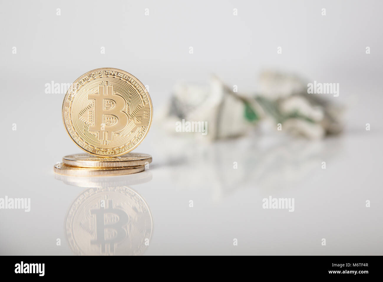 Crypto currency. Gold bitcoin coins and crumpled dollars on white ...