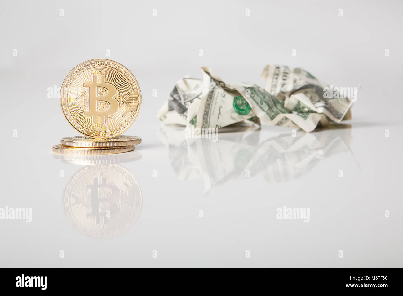 Crypto currency. Gold bitcoin coins and crumpled dollars on white ...