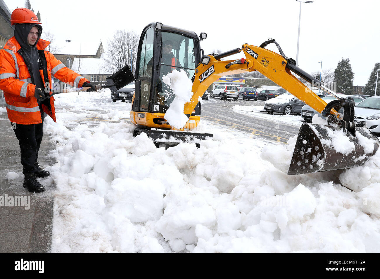 A workman and a JCB machine clearing the snow in Denny, Scotland Stock ...