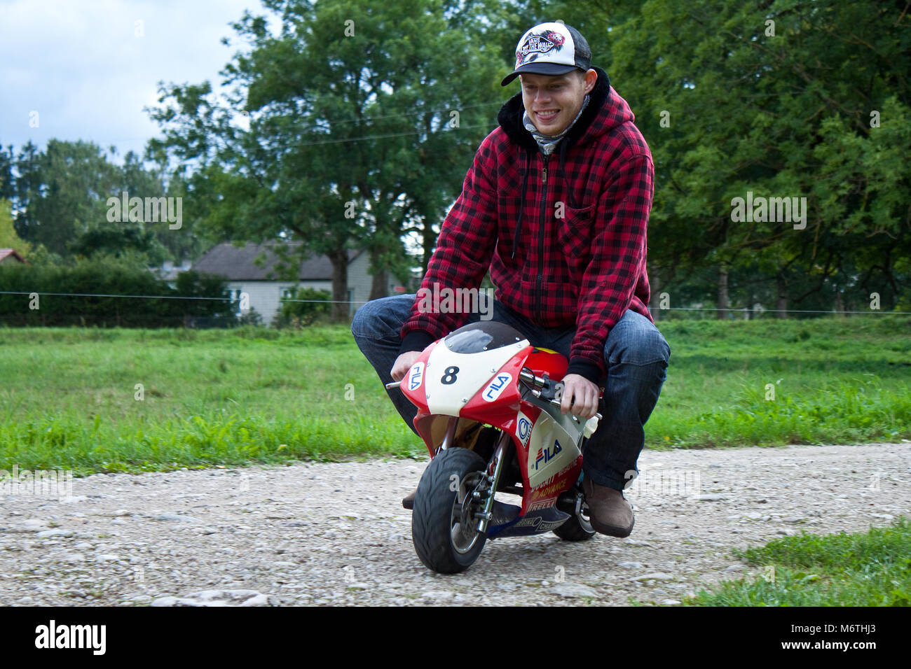 A cheerful young man riding a pocketbike Stock Photo - Alamy
