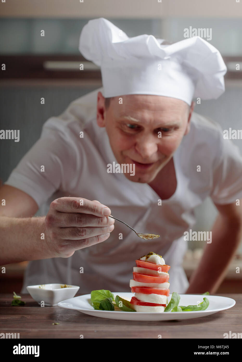 Chef prepares a snack with mozzarella and pesto sauce . Selective focus ...