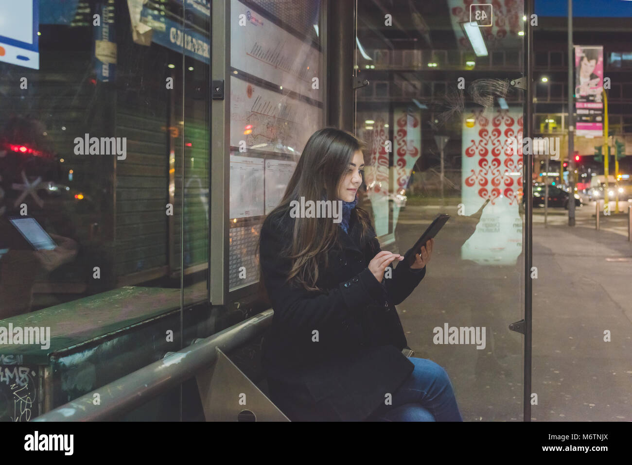 Young woman outdoor using tablet hand hold waiting bus stop ...