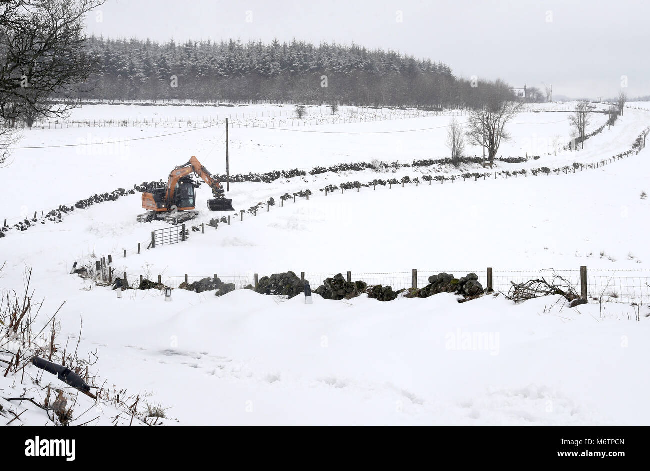 A digger clears the snow in rural Carron Valley during an attempt to ...
