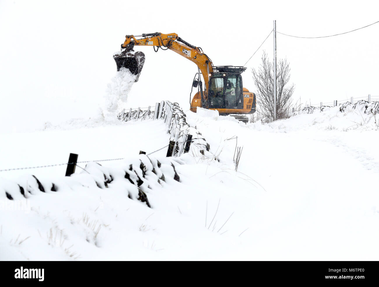 A digger clears the snow in rural Carron Valley during an attempt to ...