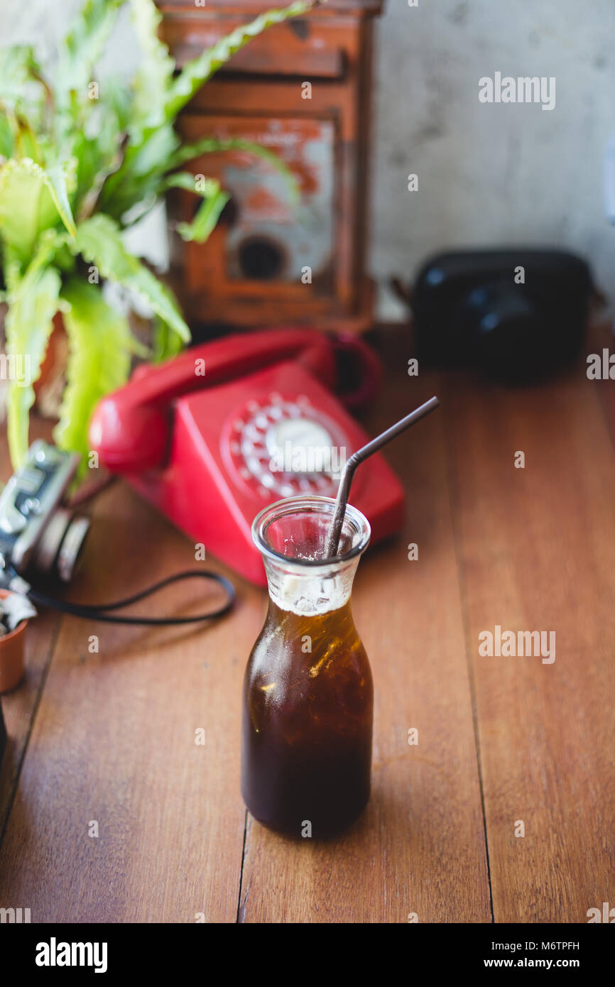 Cold black coffee with ice in bottle on wood table in coffee shop Stock ...
