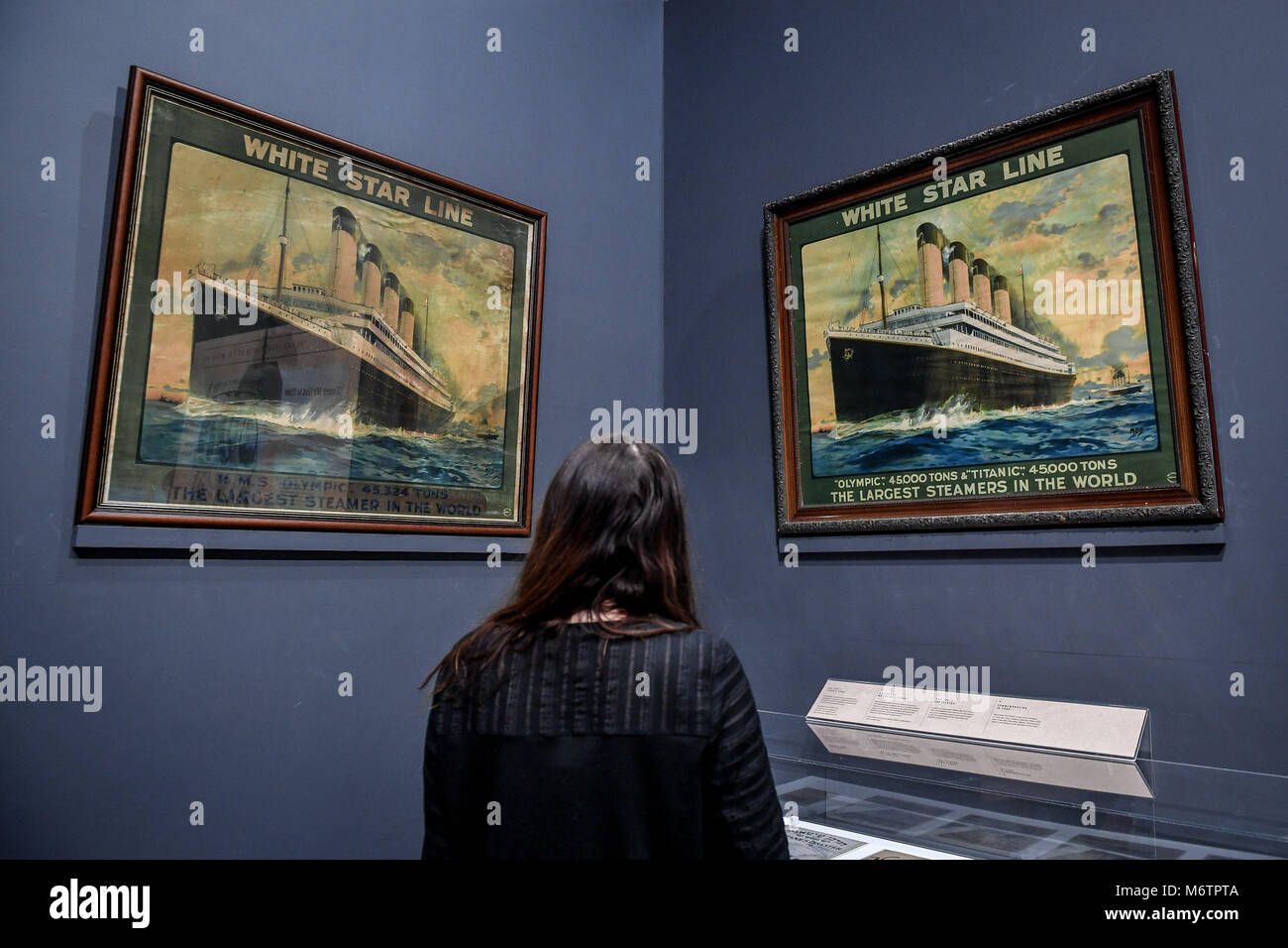 A woman looks at two publicity posters from the White Star Line company ...