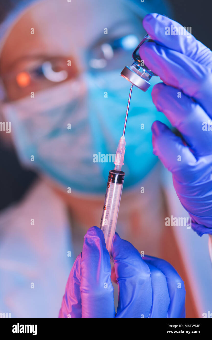 Doctor drawing up solution from vaccine bottle and filling syringe ...