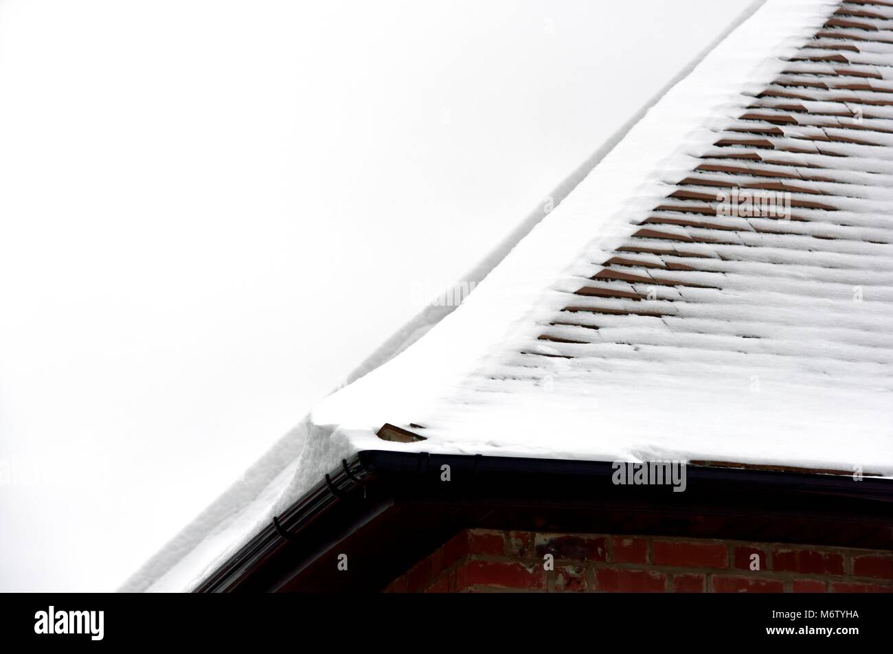 Snowdrift accumulation overhanging from a house roof Stock Photo - Alamy