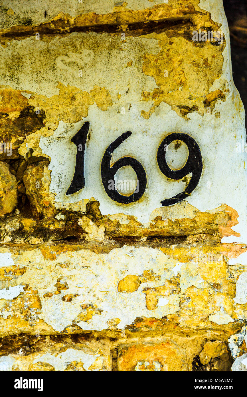 House number 169 in cast iron numbering on a yellow stone wall Stock ...