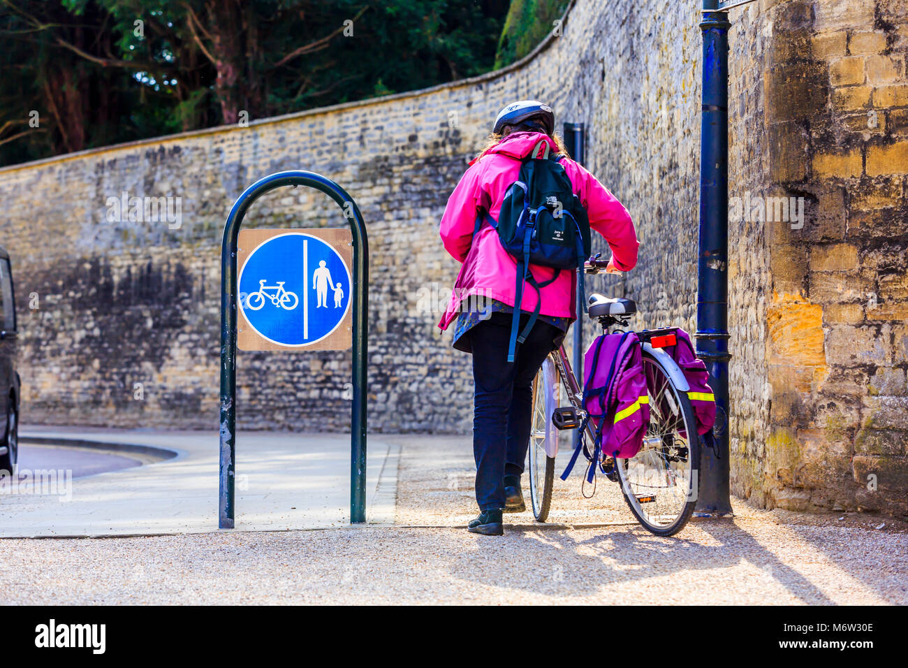 A cyclist having to dismount and walk through a passage Stock Photo - Alamy