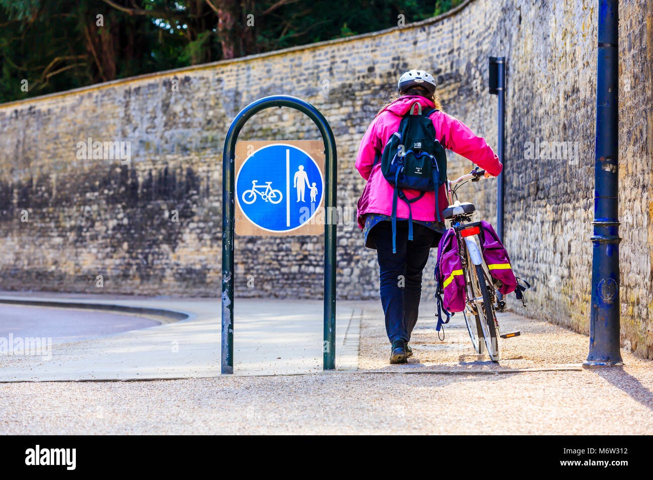 A cyclist having to dismount and walk through a passage Stock Photo - Alamy