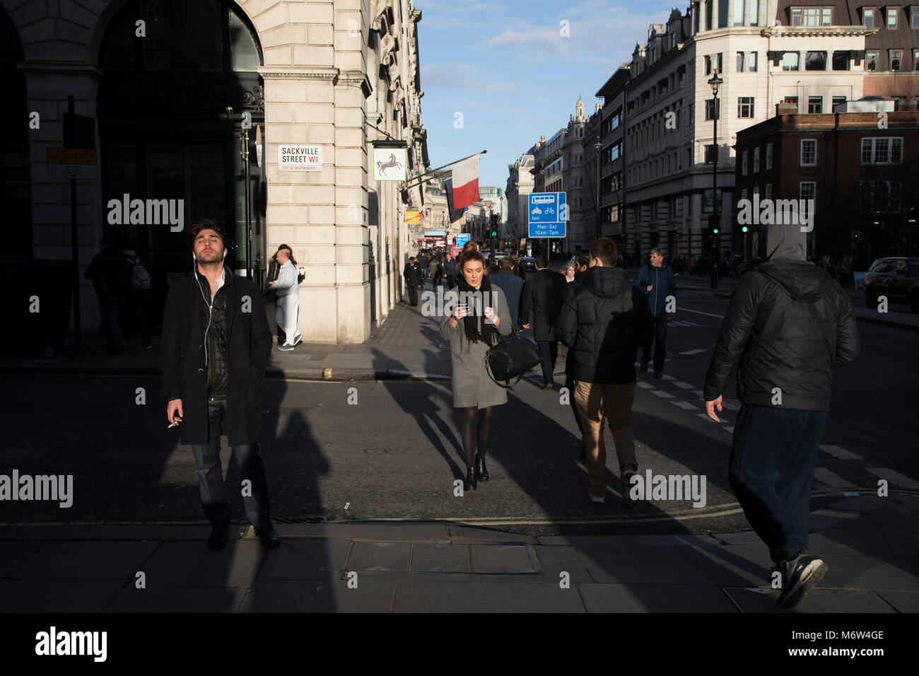 Evening light illuminating people walking along Piccadilly as a man ...