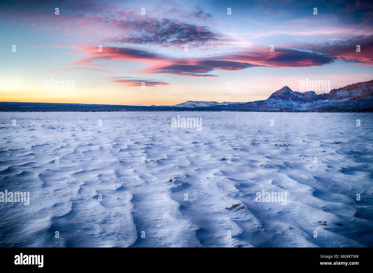 Sunset over field of icy snow and background mountains in Southern Utah ...