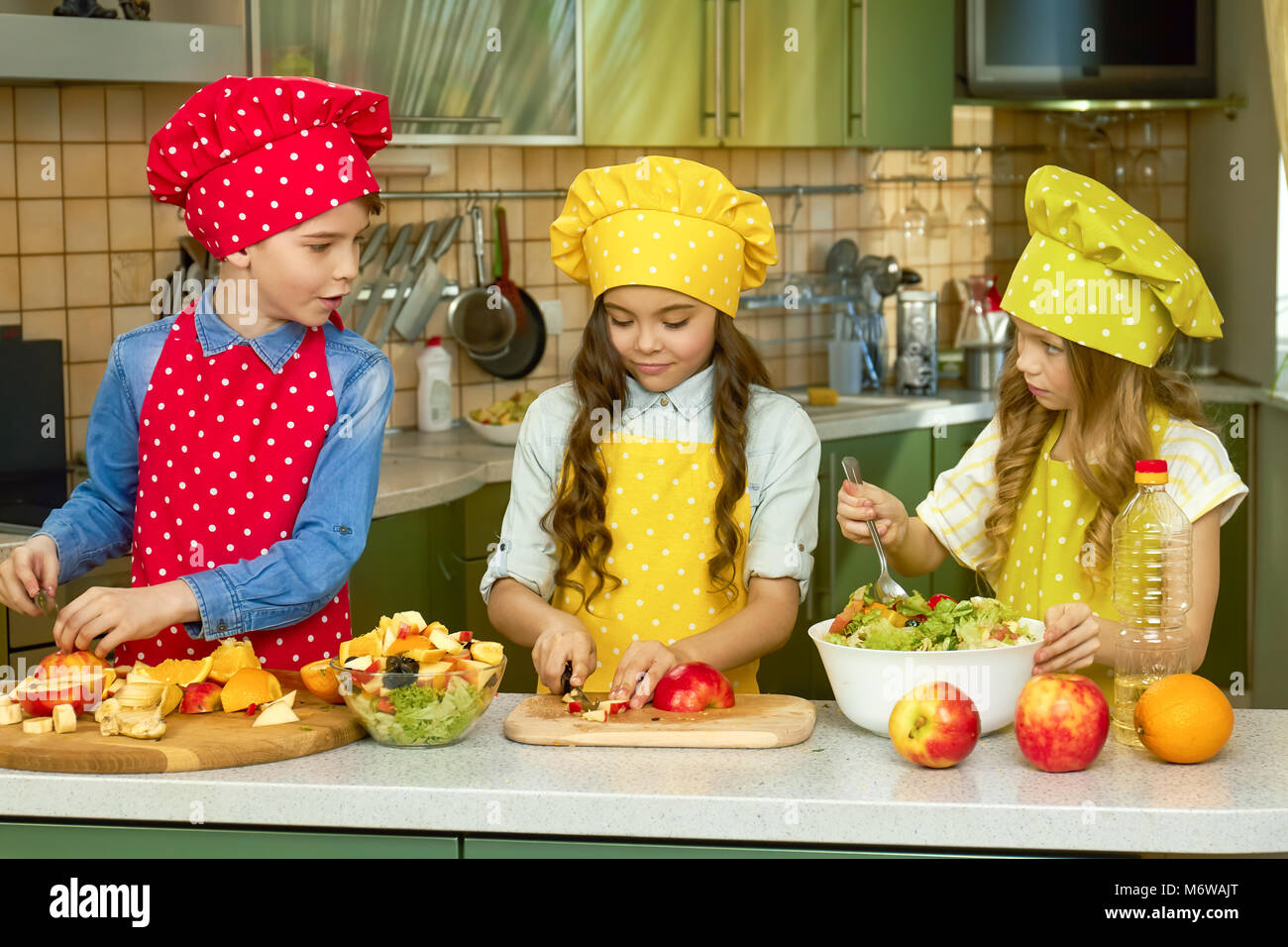 Three kids making salad, kitchen Stock Photo - Alamy