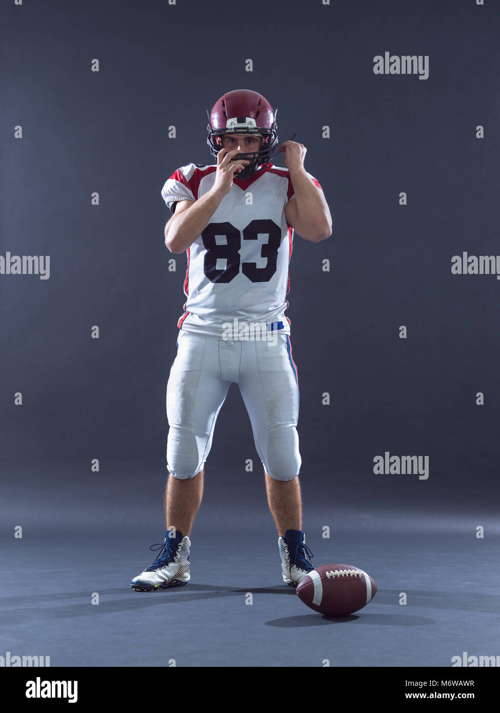 Portrait of a strong muscular American Football Player isolated on gray ...