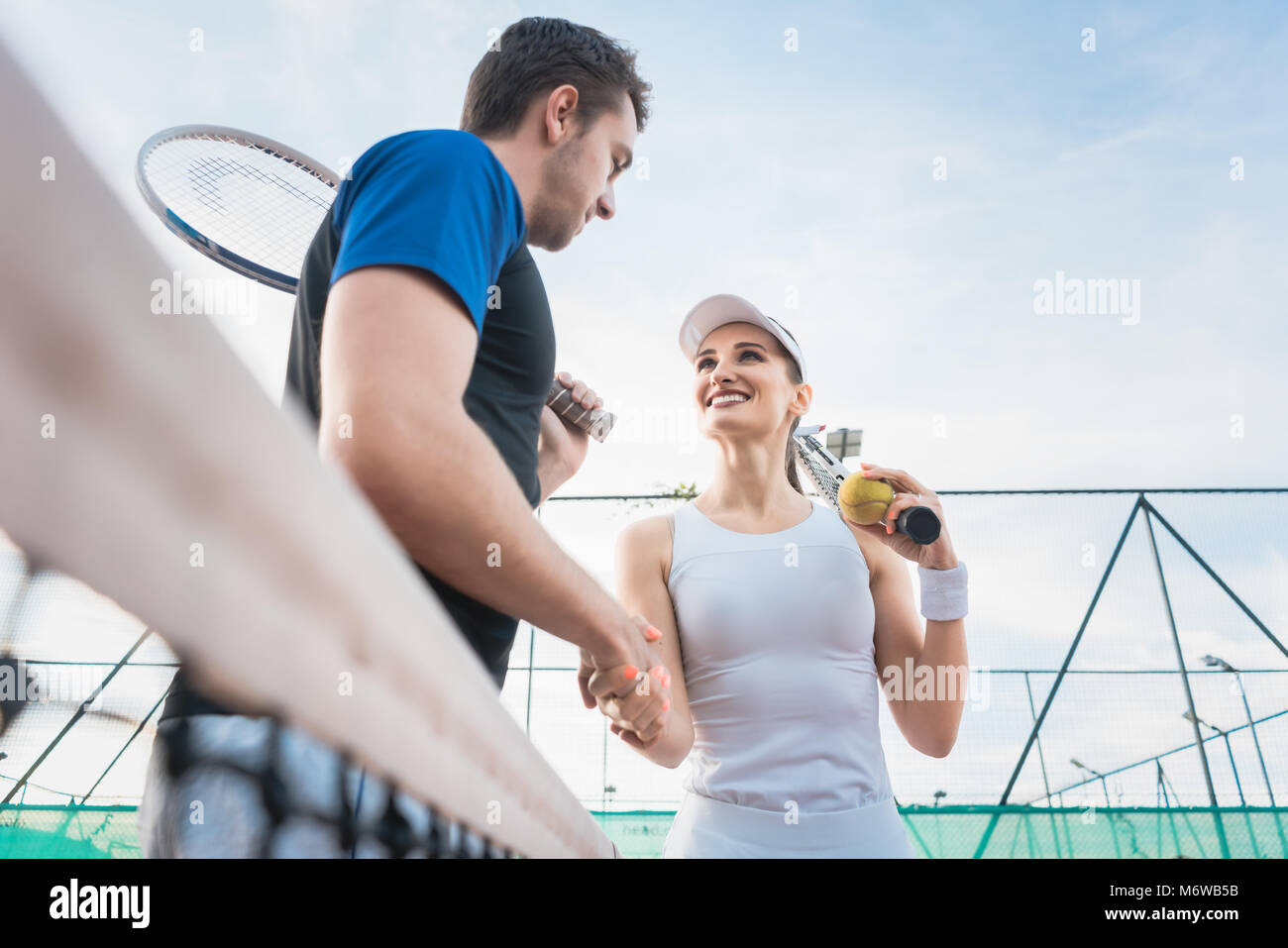 Tennis player man and woman giving handshake after match at the net ...