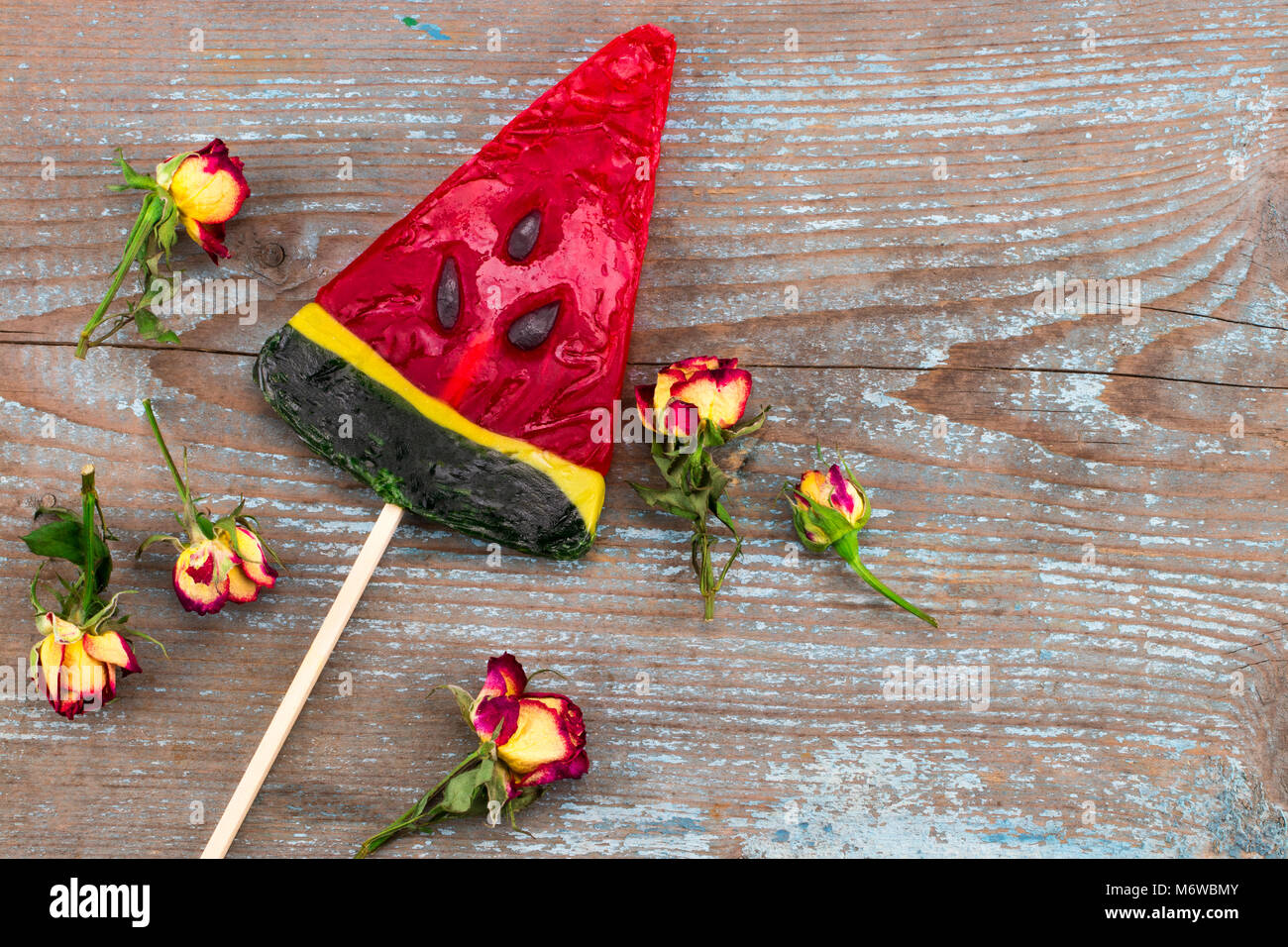 Lollipop and beautiful flowers roses on wooden background. With copy ...